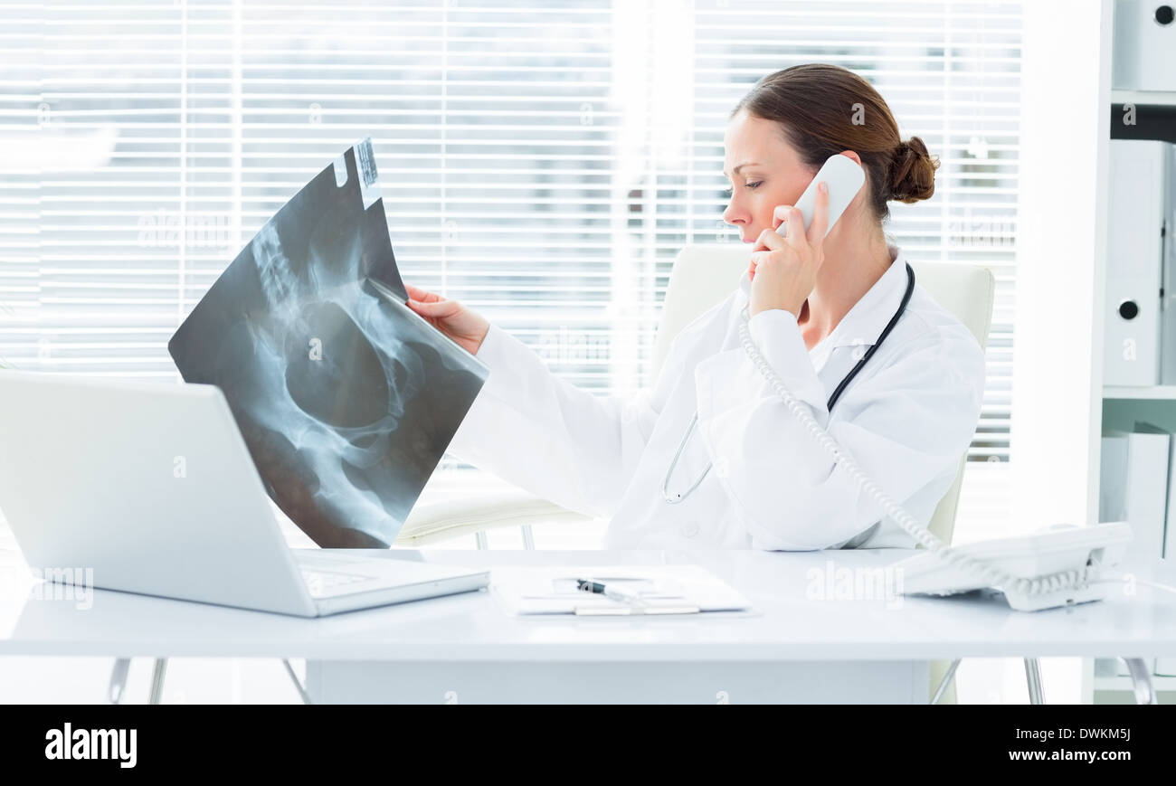 Doctor using telephone while studying Xray Stock Photo - Alamy