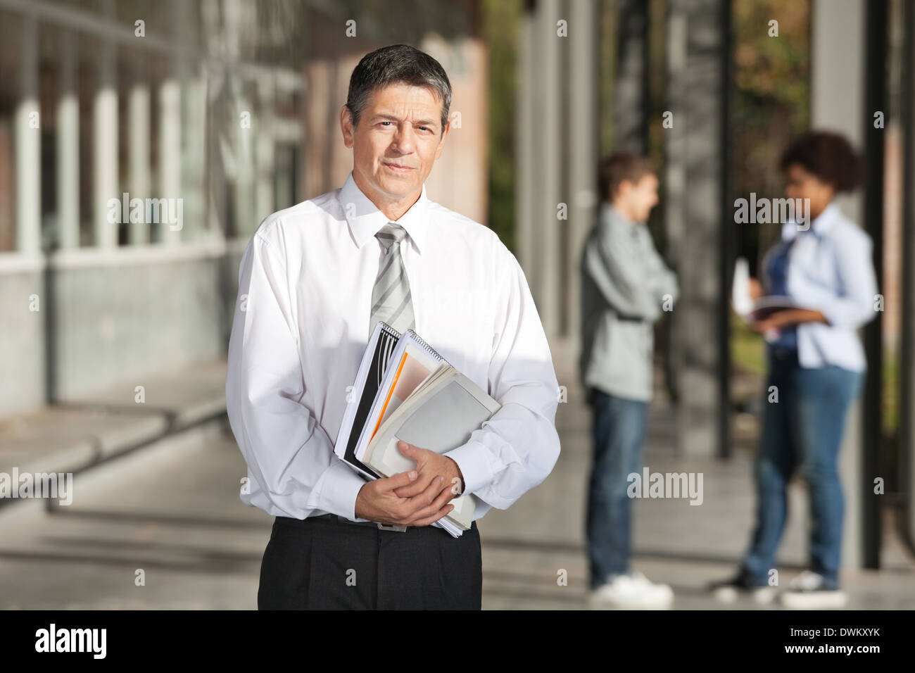 Confident Professor With Books Standing On College Campus Stock Photo ...