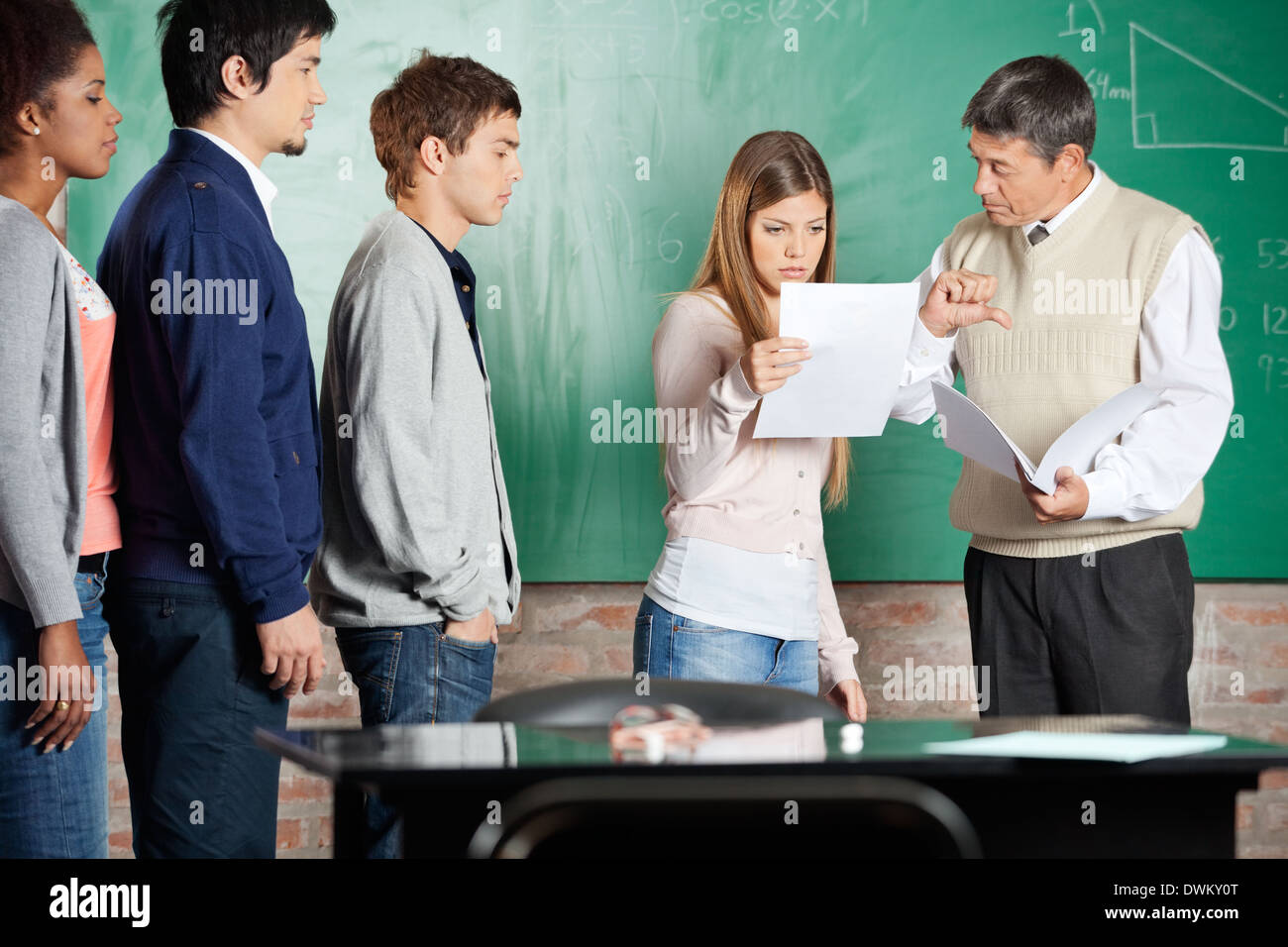 Teacher Gesturing Thumbsdown While Student Looking At Report In Stock ...