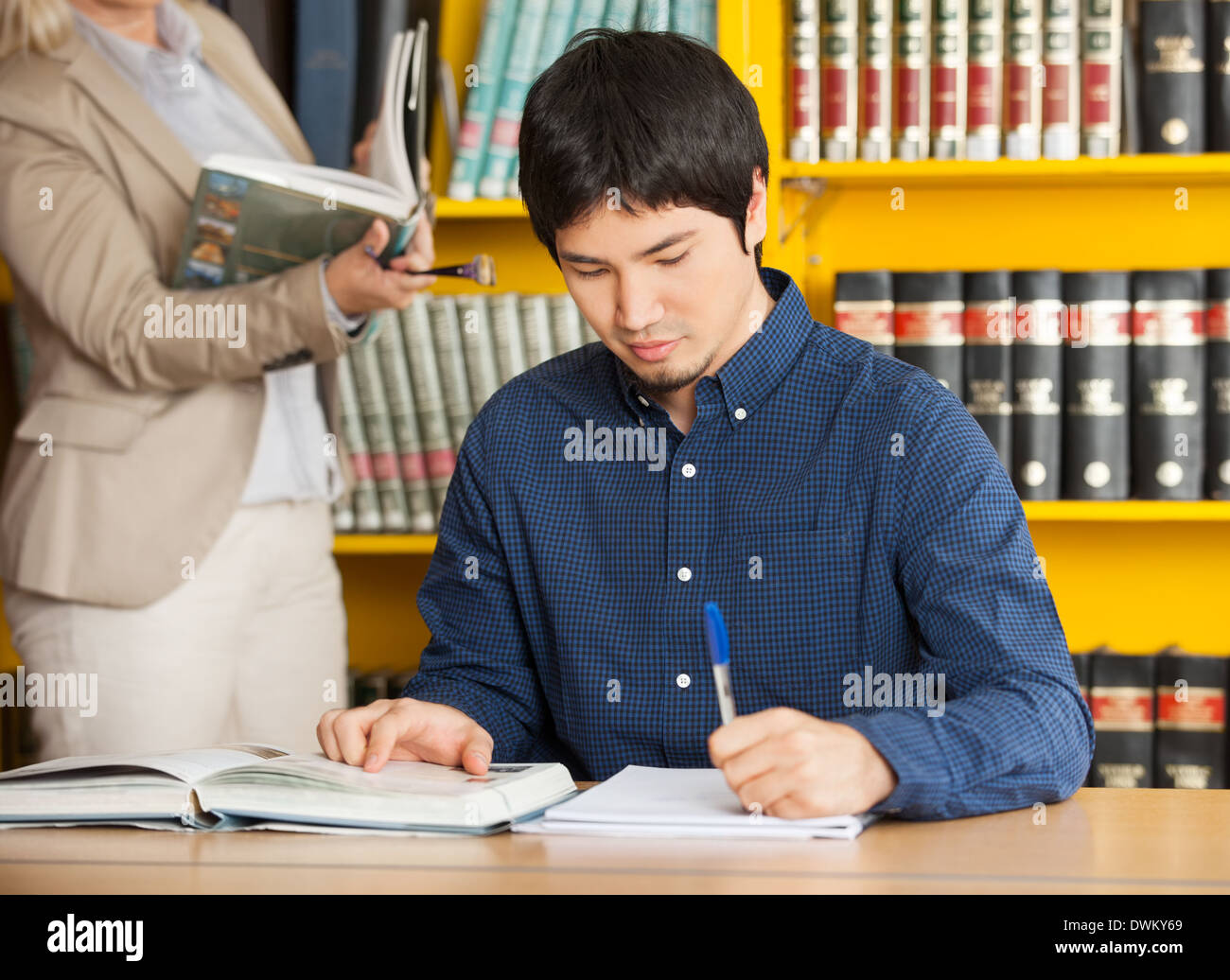 Student Writing In Book At College Library Stock Photo - Alamy