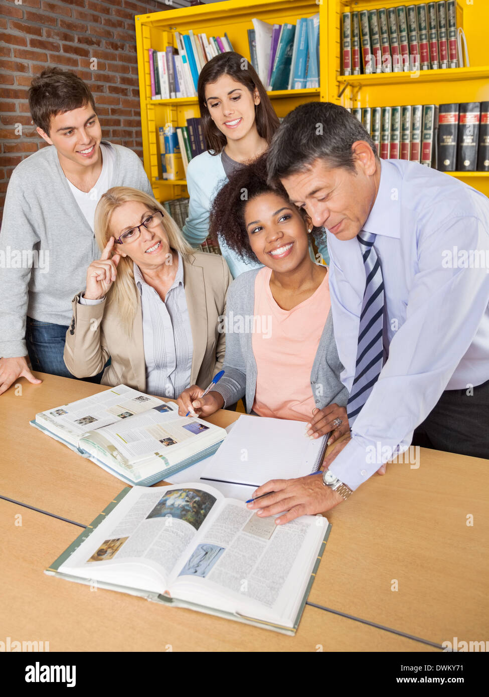 Teachers And Students Discussing Over Book In Library Stock Photo - Alamy