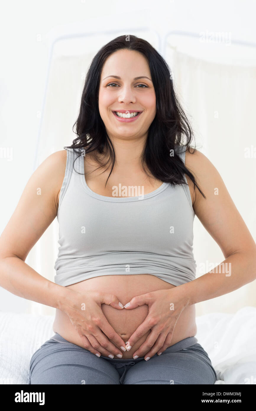 Happy pregnant woman making heart shape on belly Stock Photo - Alamy