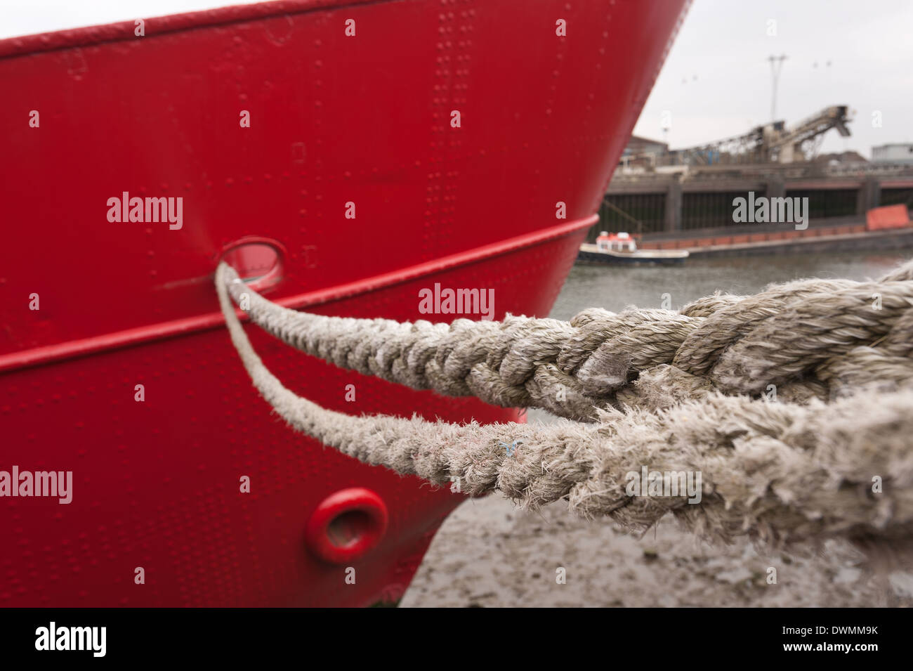 strong mooring rope as a holdfast to keep bright red steel boat hull ...