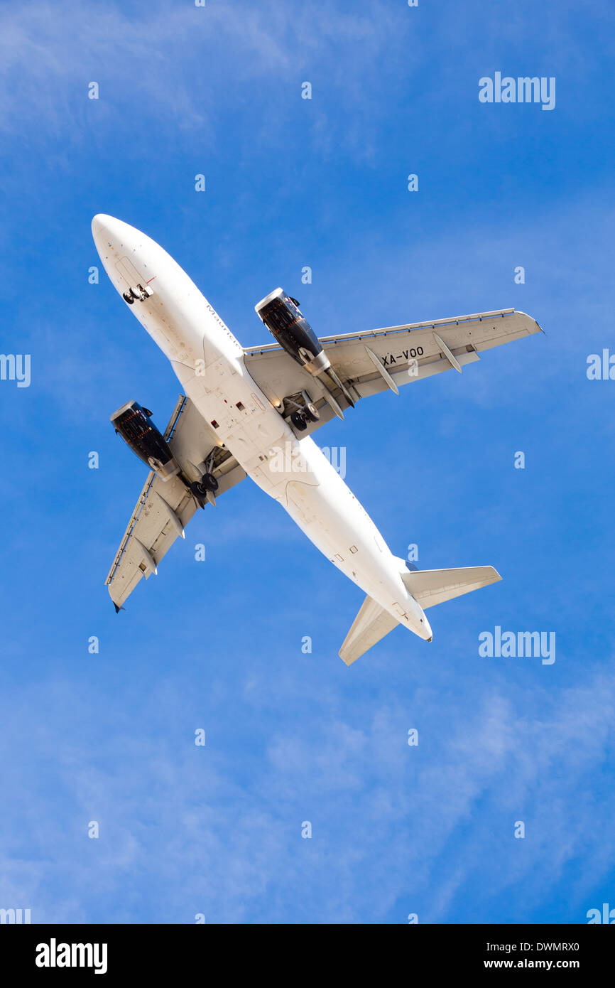 Airplane flying overhead with blue sky and the bottom of the airplane ...