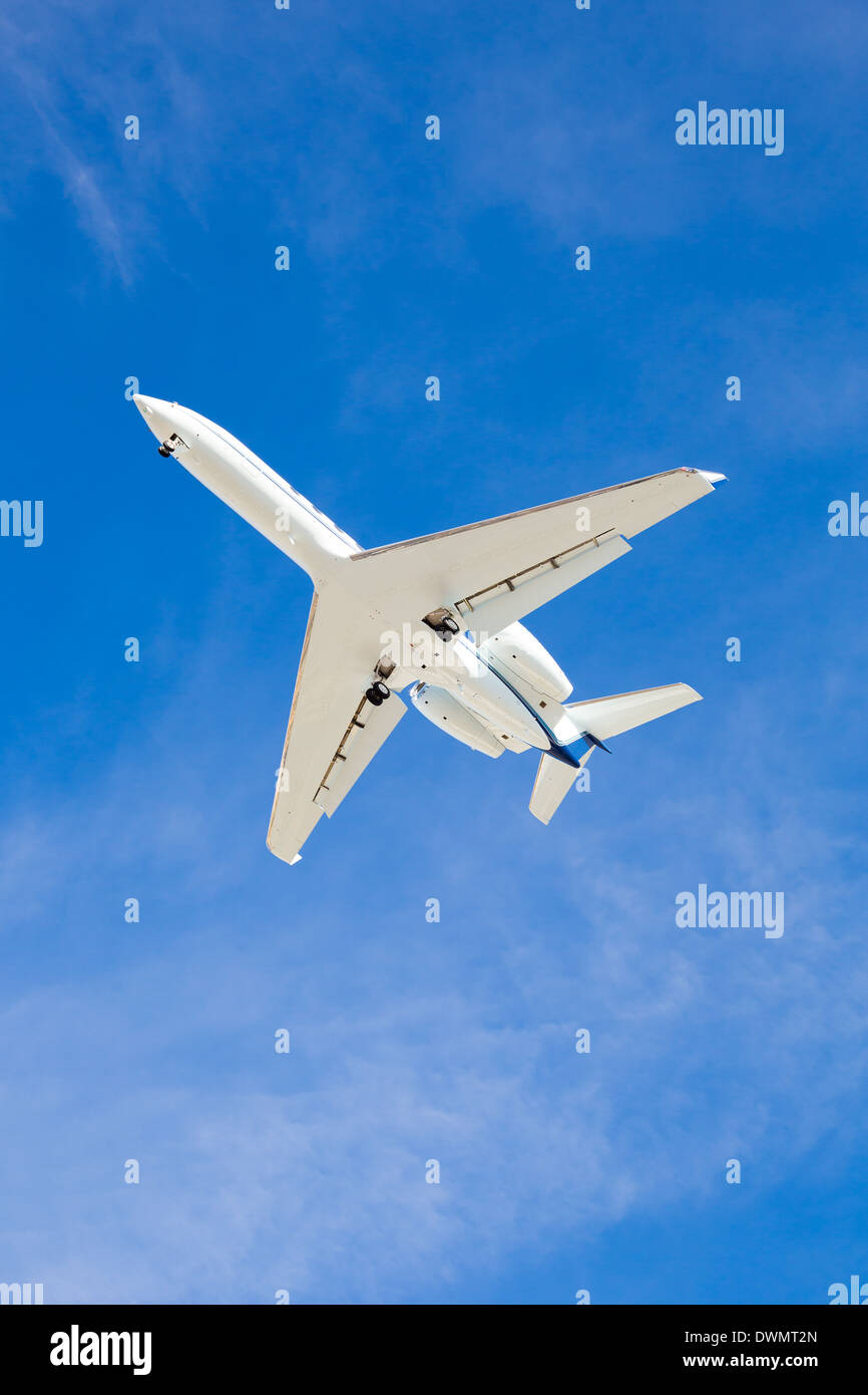 Airplane flying overhead with blue sky and the bottom of the airplane ...