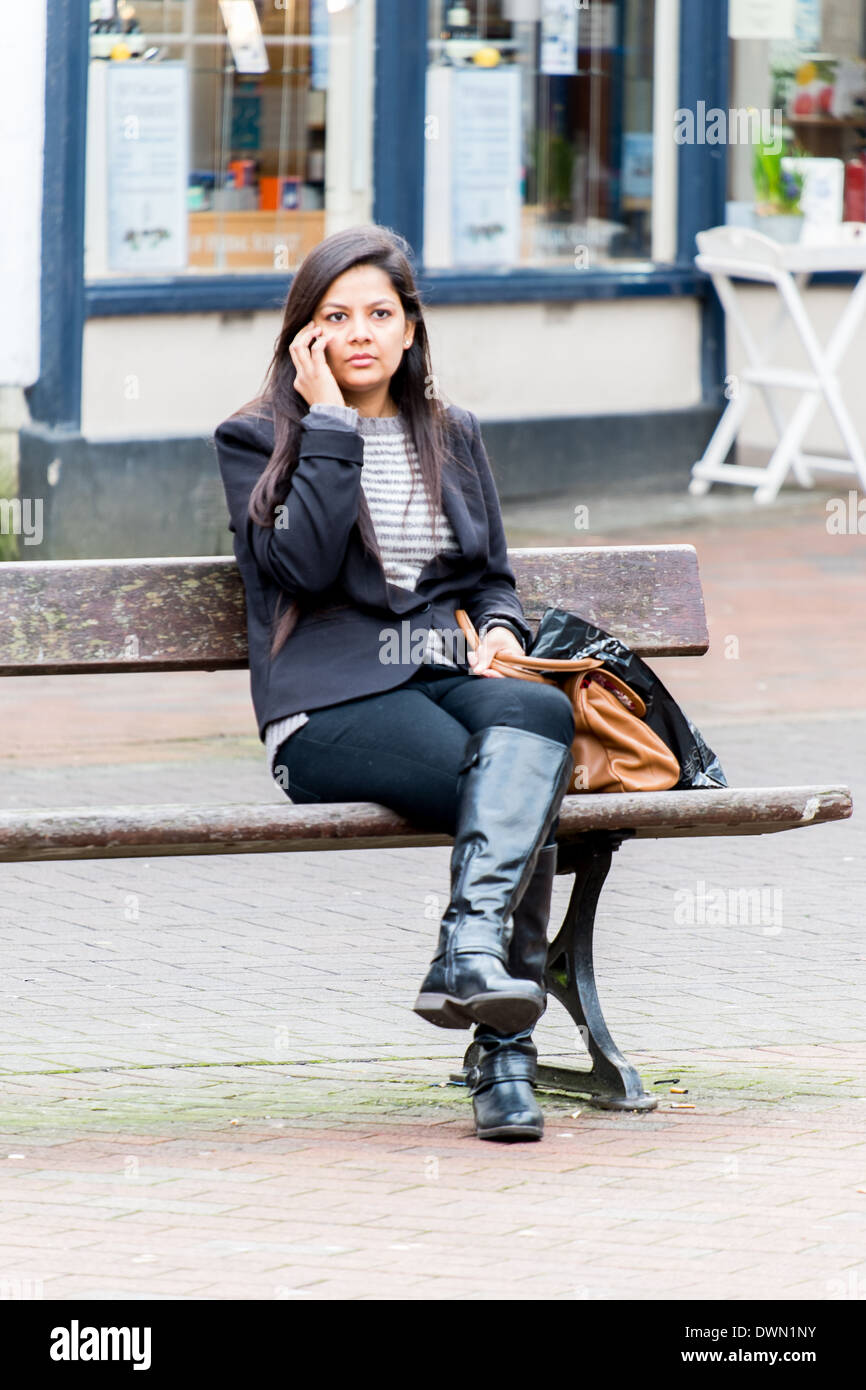 Female using mobile phone sat on city centre bench Stock Photo - Alamy