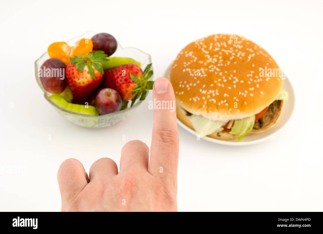 Finger choosing between hamburger and fruits. Food on white background ...