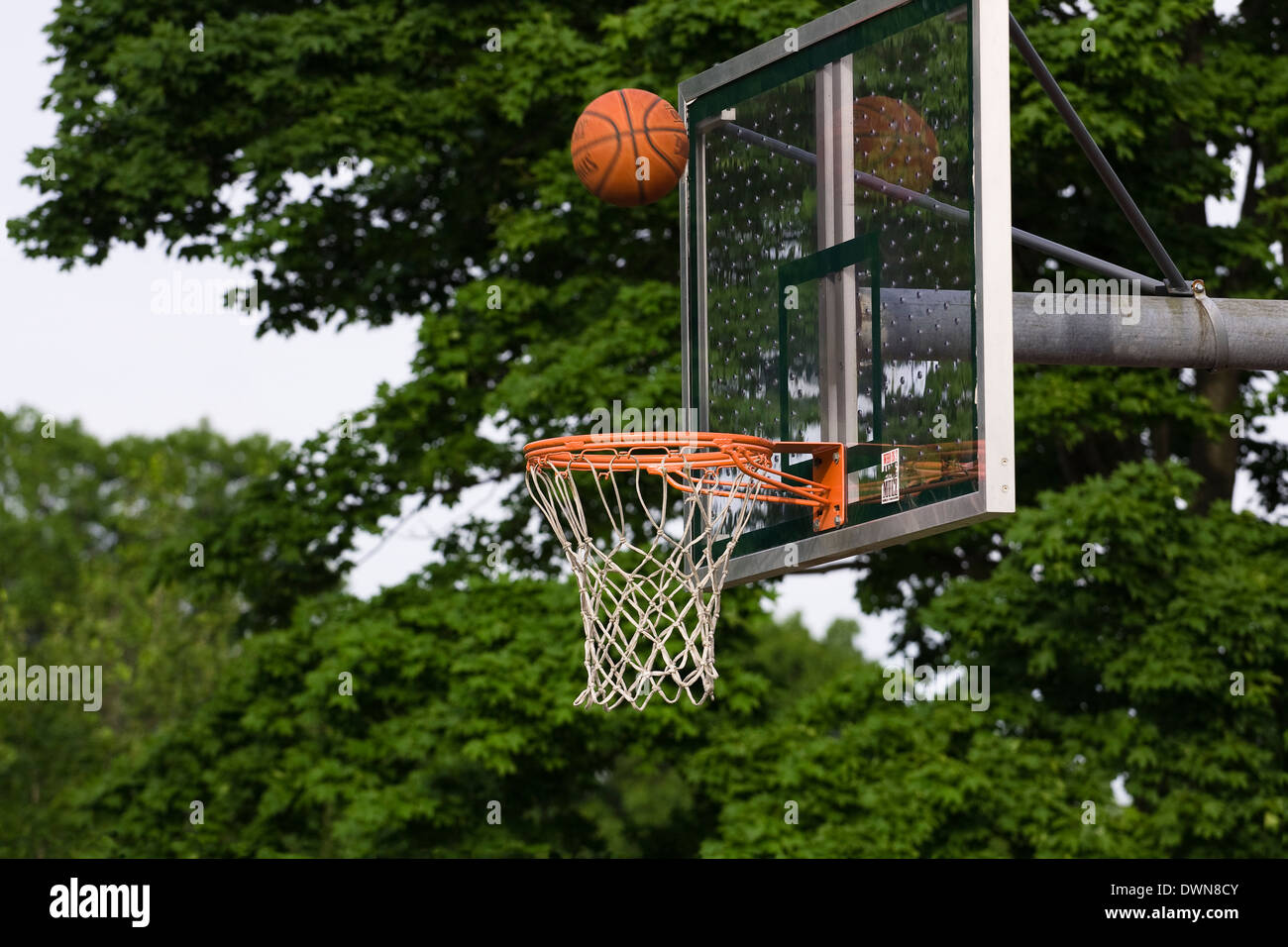 A basketball above the rim with net in a city park Stock Photo - Alamy