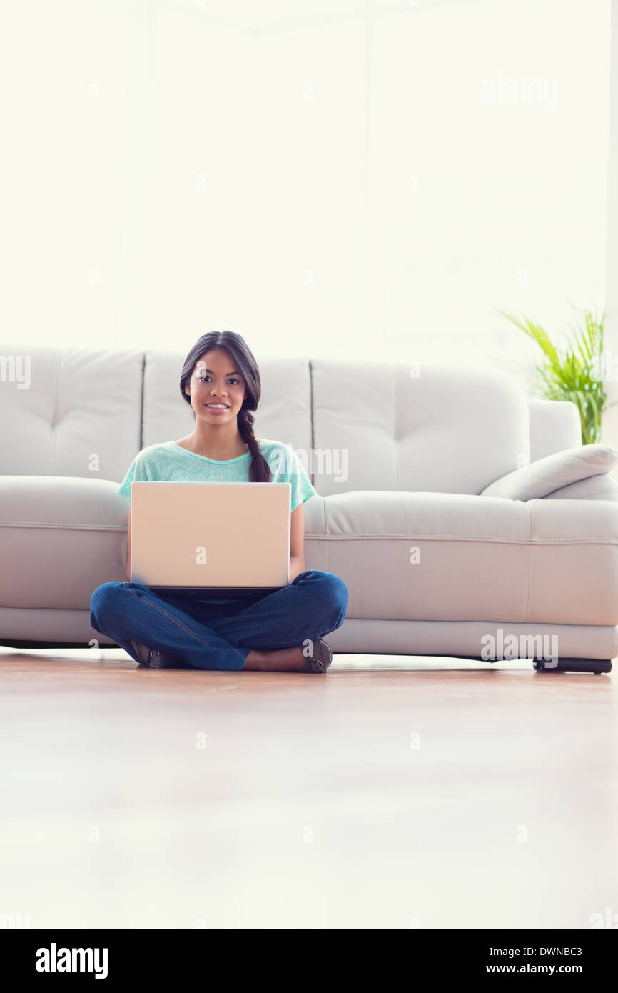 Pretty girl sitting on floor using her laptop smiling at camera Stock ...