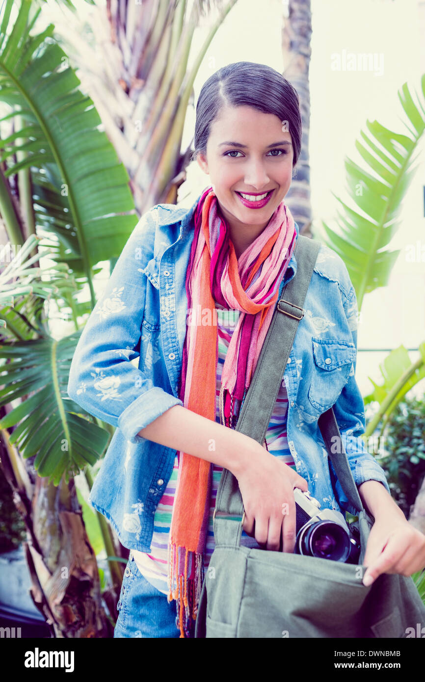 Young happy woman taking camera out from her bag outside Stock Photo ...