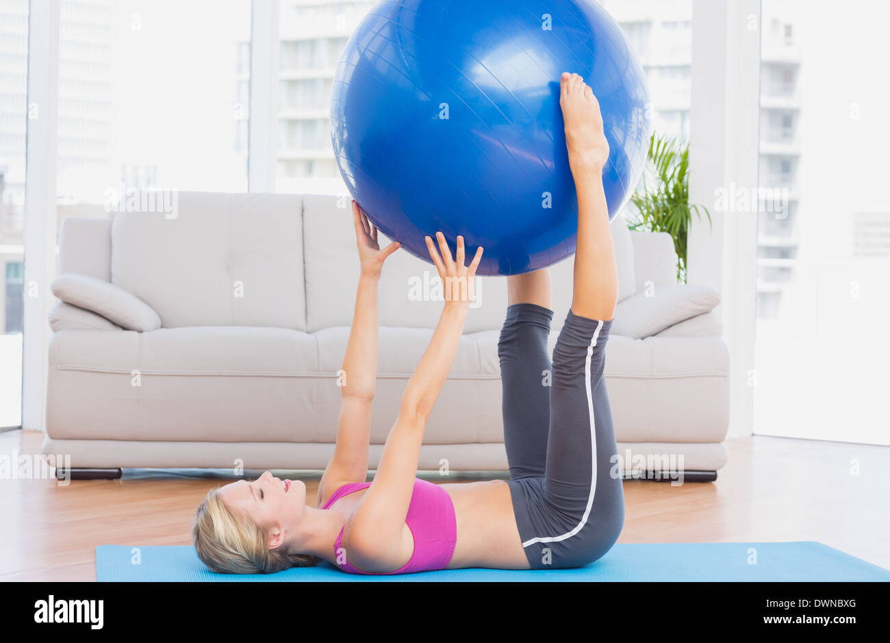 Cheerful fit blonde holding exercise ball between legs Stock Photo - Alamy