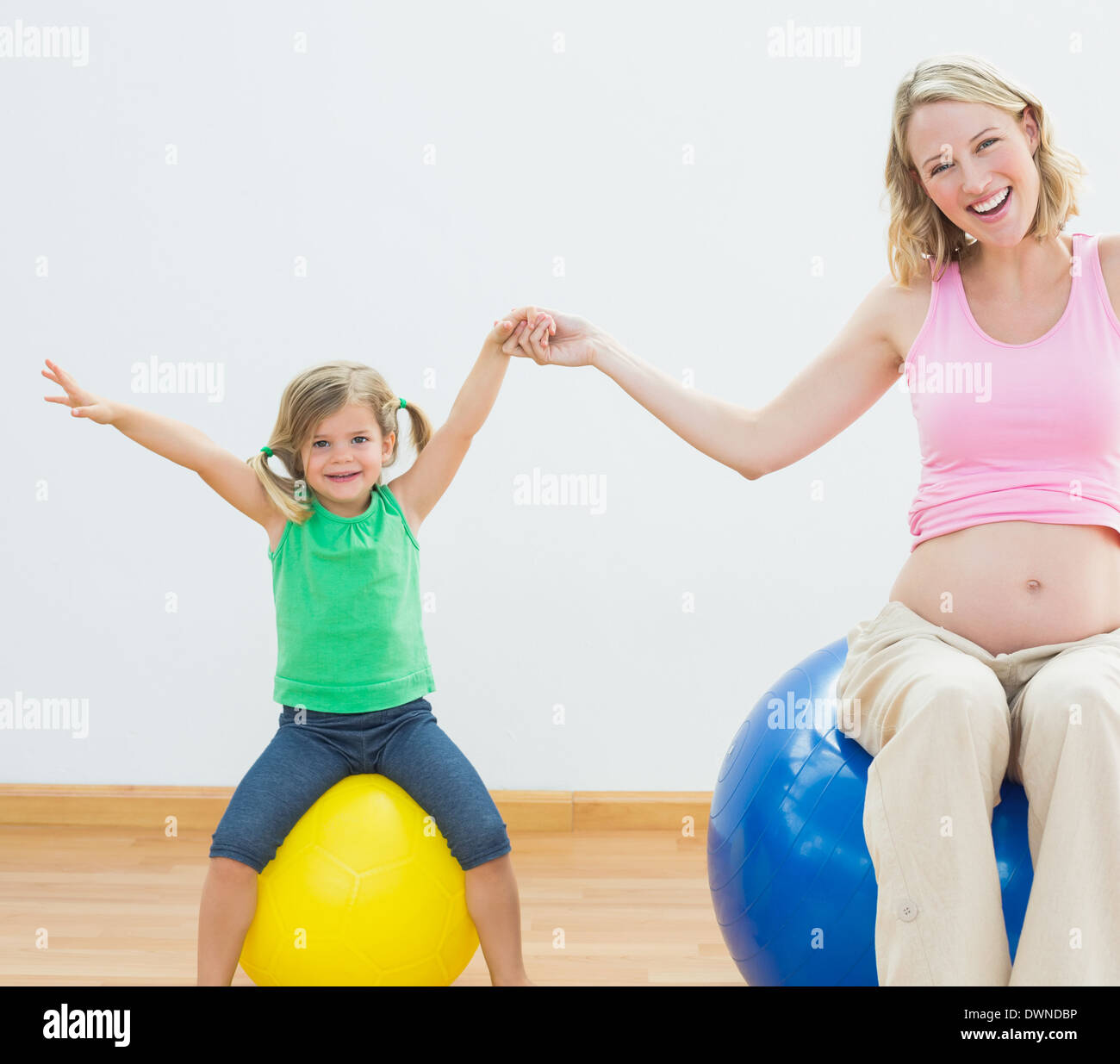 Happy pregnant woman bouncing on exercise ball with young daughter Stock Photo Alamy