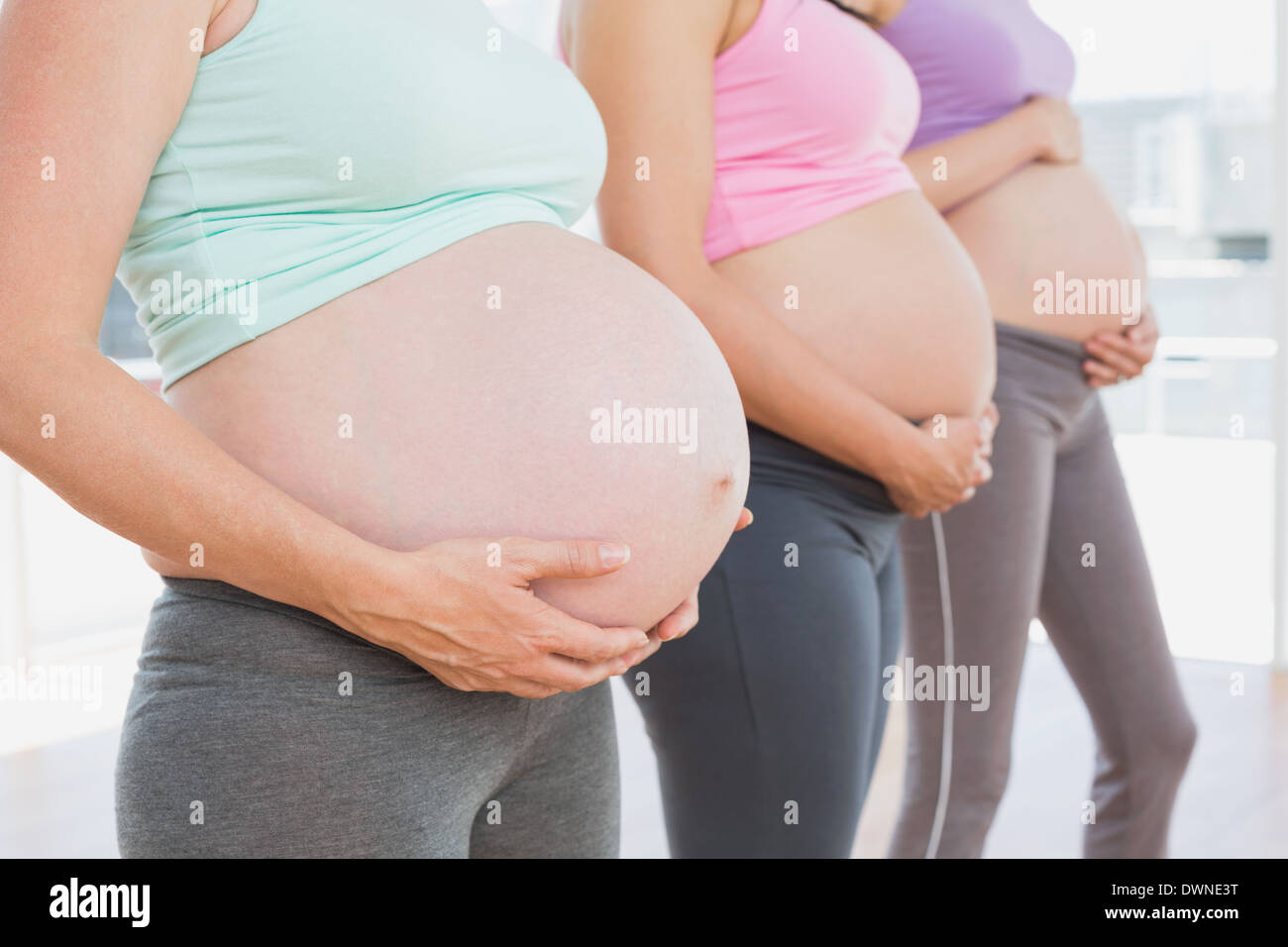 Pregnant women standing in a line holding their bumps Stock Photo - Alamy