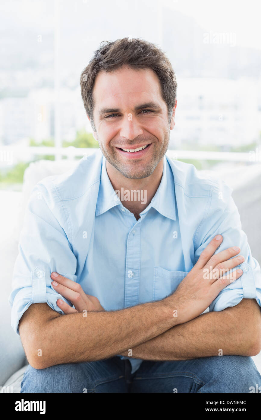Cheerful man sitting on the couch smiling at camera Stock Photo - Alamy