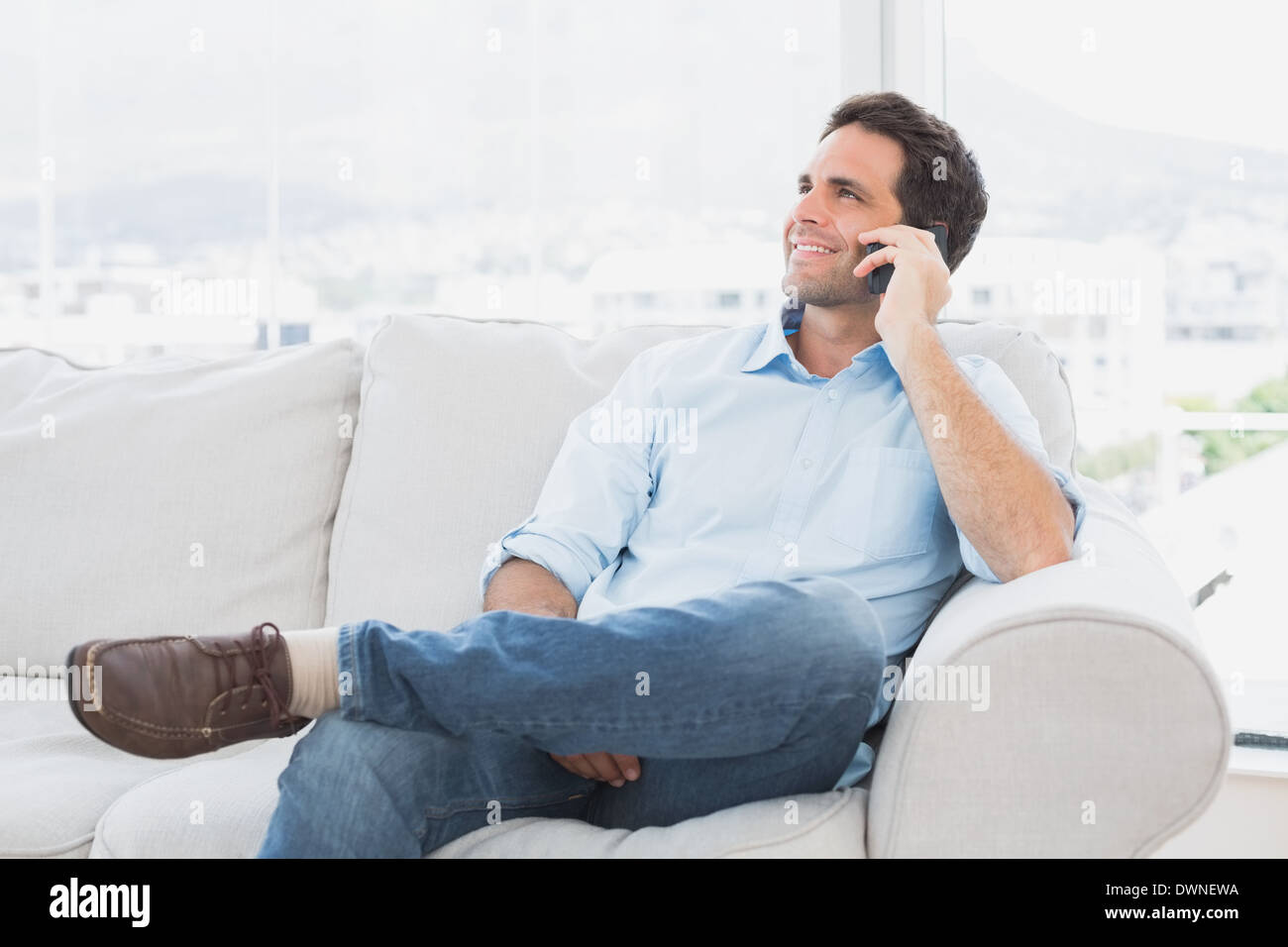 Cheerful man sitting on the couch making a phone call Stock Photo - Alamy