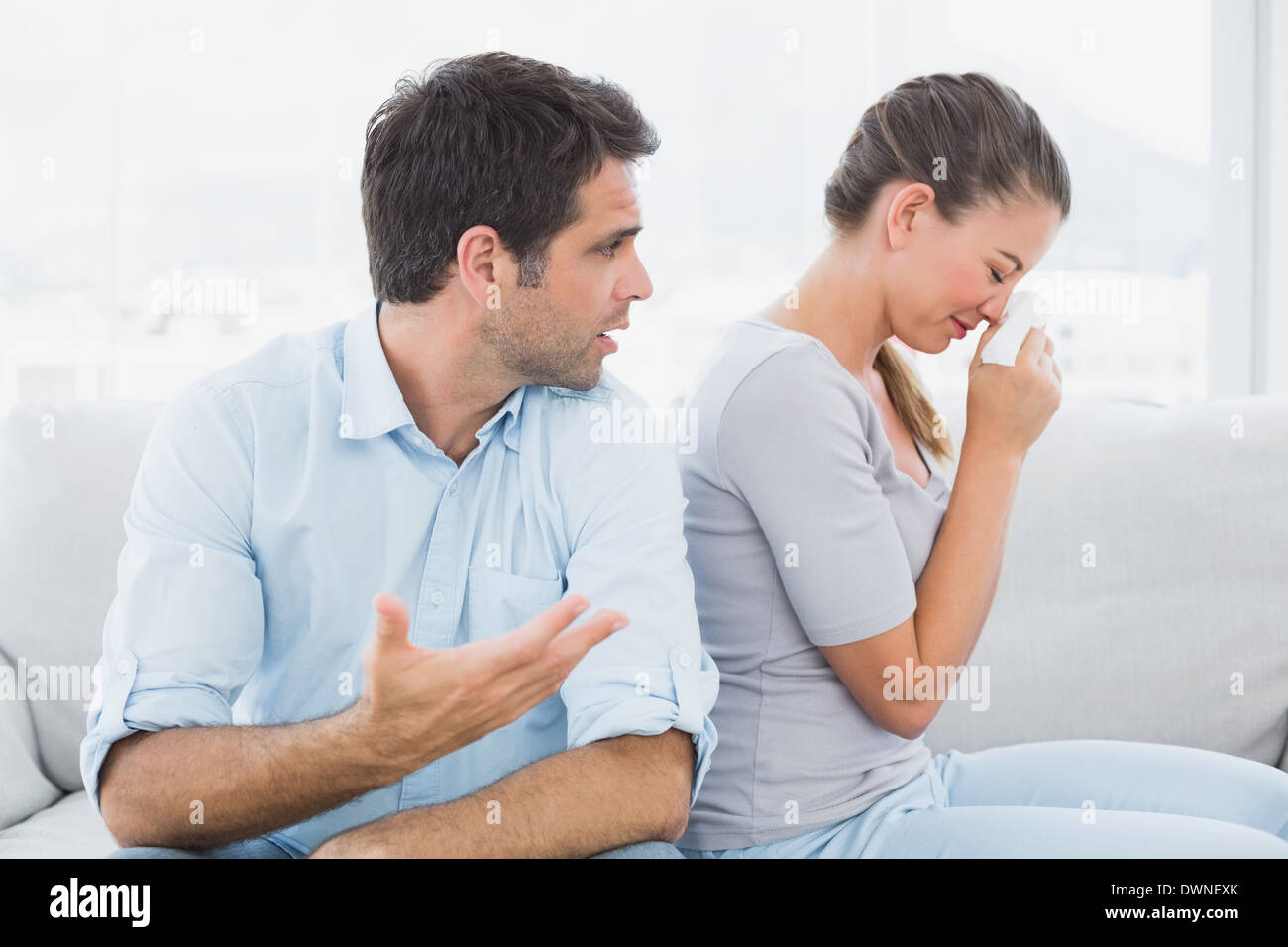 Man pleading with his crying partner on the couch Stock Photo - Alamy