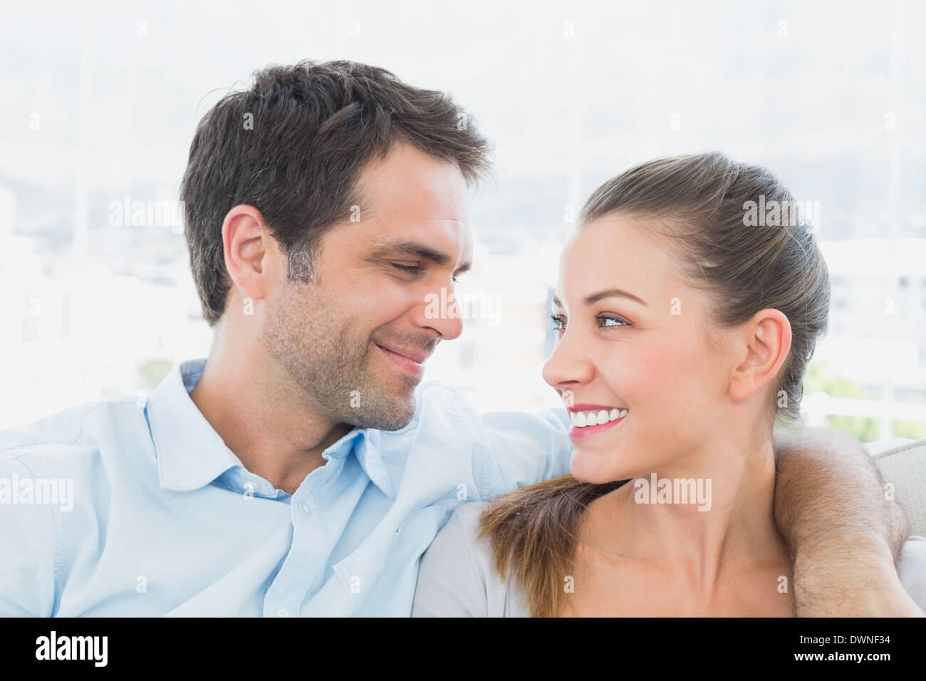 Couple sitting on the sofa smiling at each other Stock Photo - Alamy