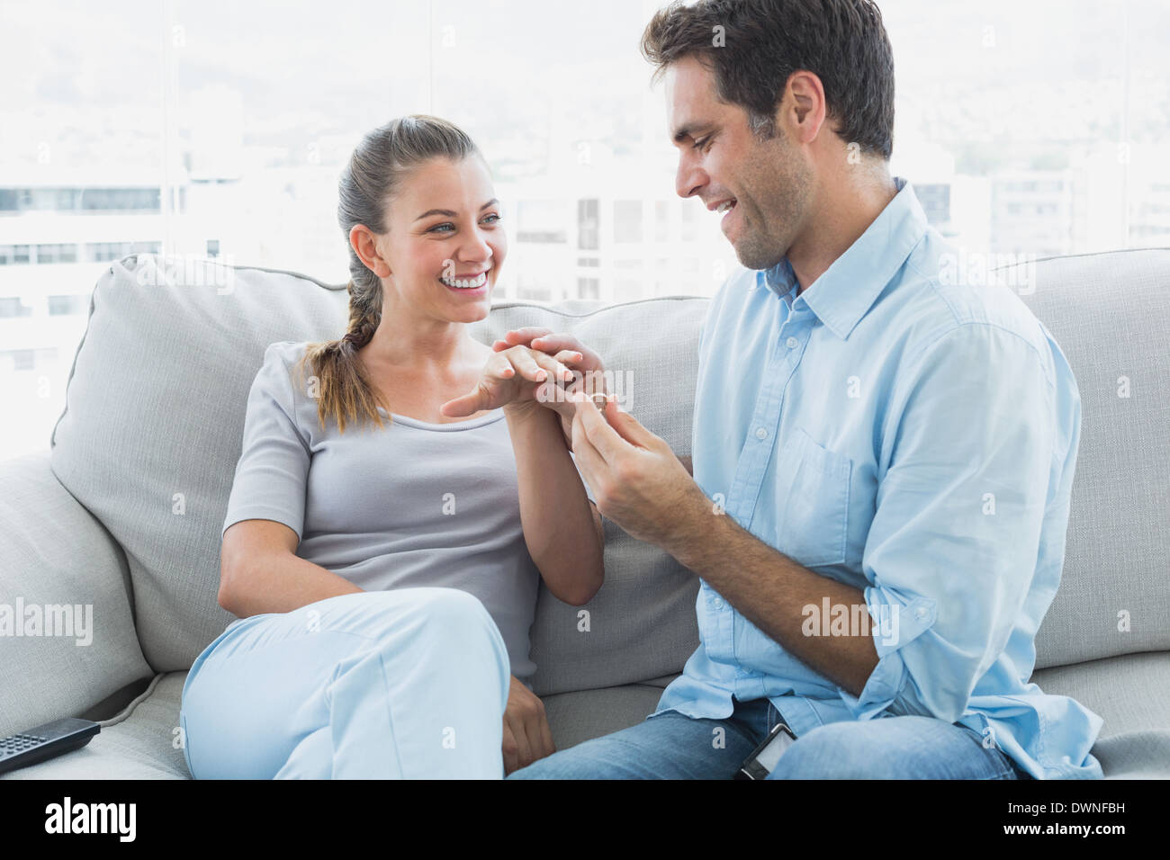Excited couple getting engaged on their sofa Stock Photo - Alamy