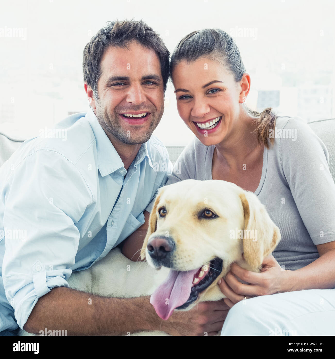 Happy couple petting their yellow labrador on the couch Stock Photo - Alamy