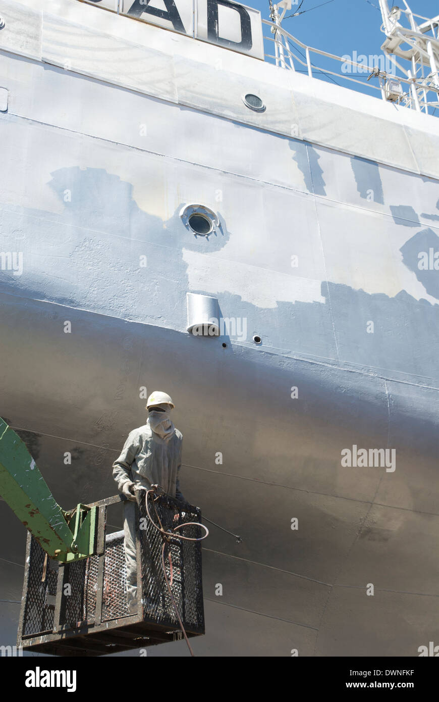 Dock worker spray paints a boat, Cape Town harbour, January 2011 Stock ...