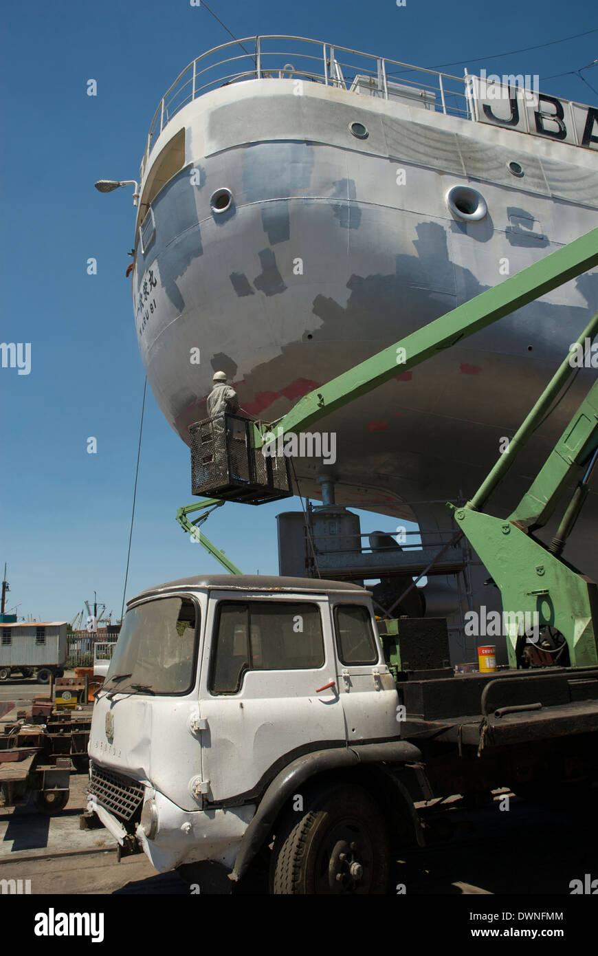 Dock worker spray paints a boat, Cape Town harbour, January 2011 Stock ...