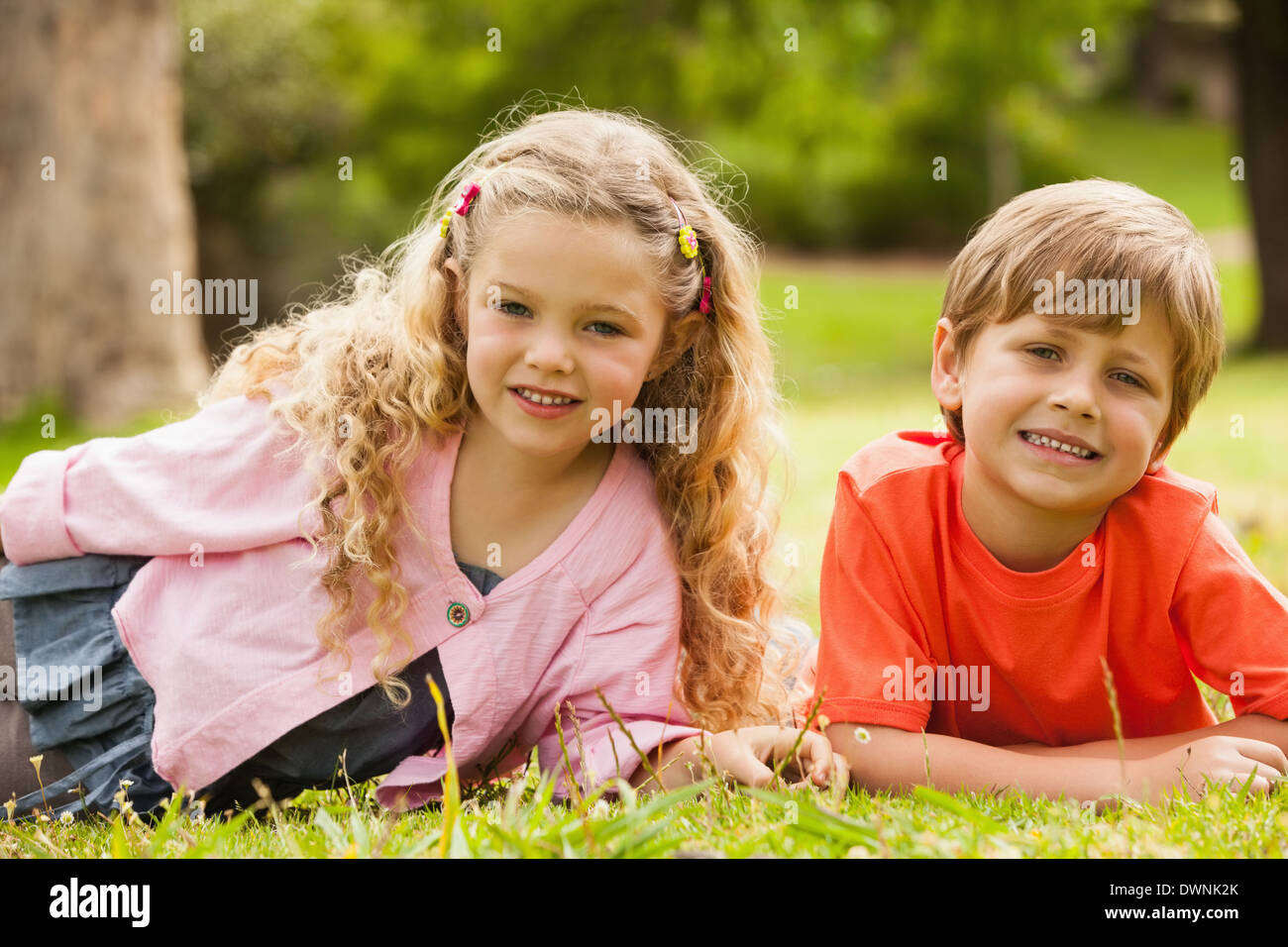 Two smiling kids lying at park Stock Photo - Alamy