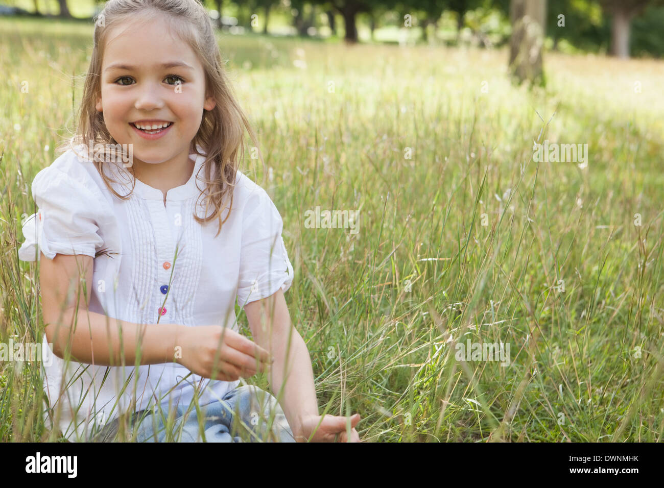 Smiling relaxed young girl sitting in field Stock Photo - Alamy