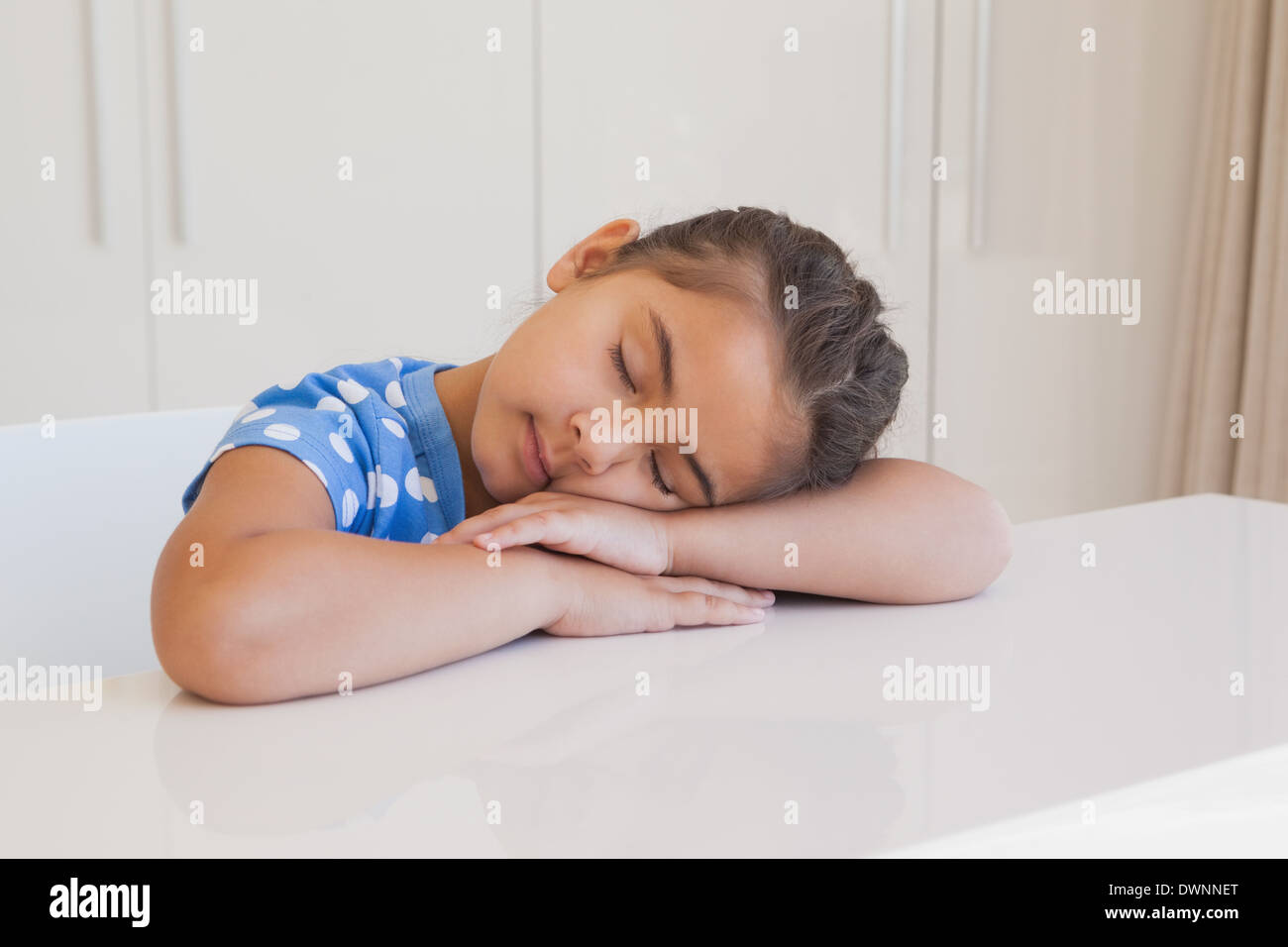 Cute young girl resting head on table Stock Photo - Alamy