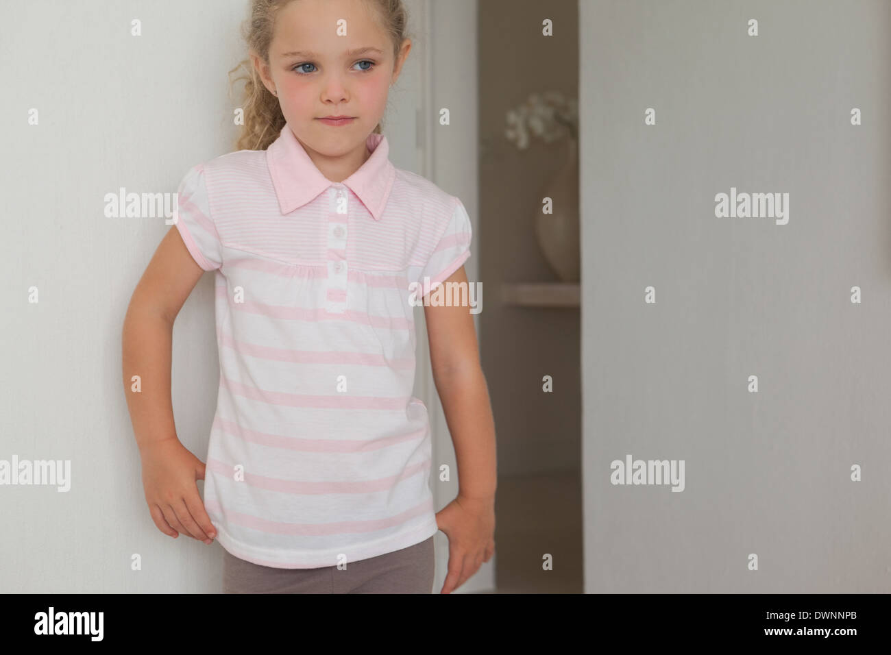Serious girl standing against wall Stock Photo - Alamy