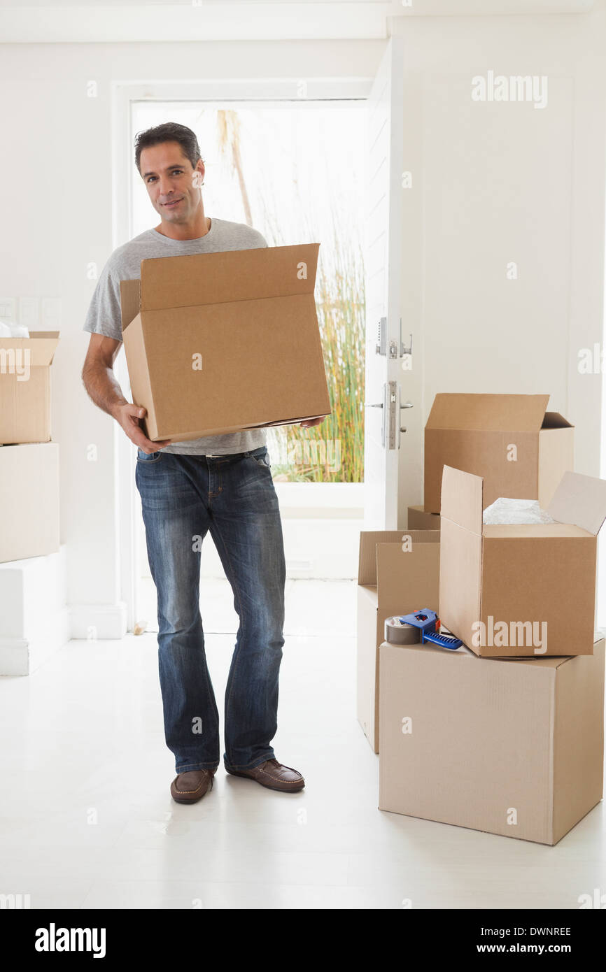 Smiling man carrying boxes in new house Stock Photo - Alamy