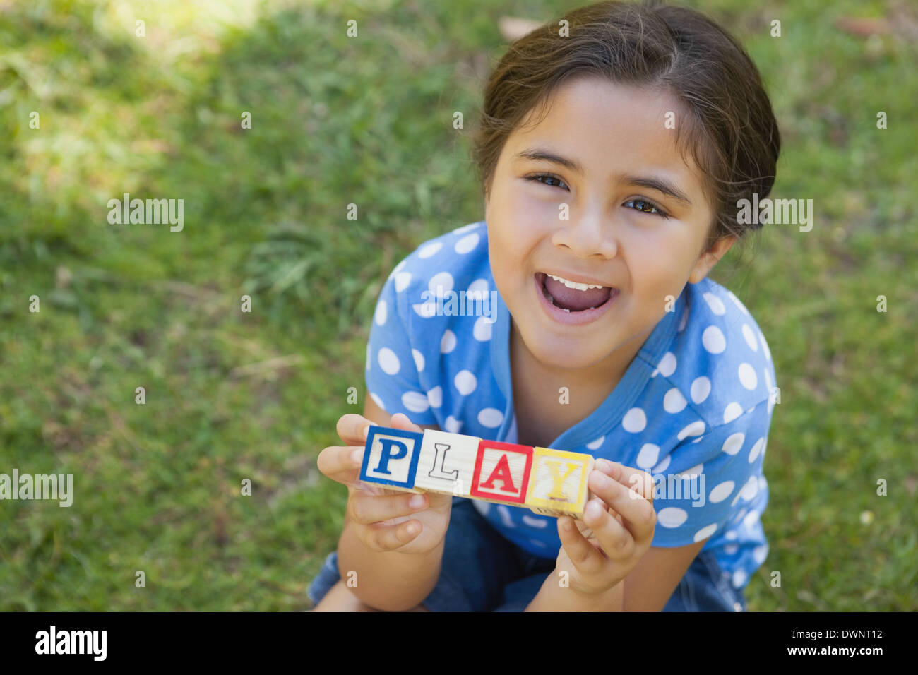 Happy girl holding block alphabets as 'play' at park Stock Photo - Alamy