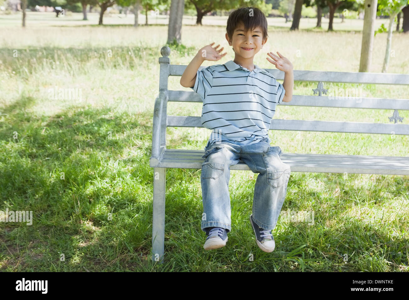 Happy young boy sitting on bench at park Stock Photo - Alamy