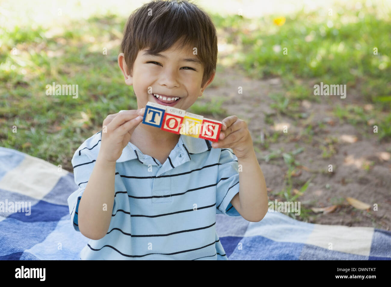 Happy boy holding block alphabets as toys' at park Stock Photo - Alamy