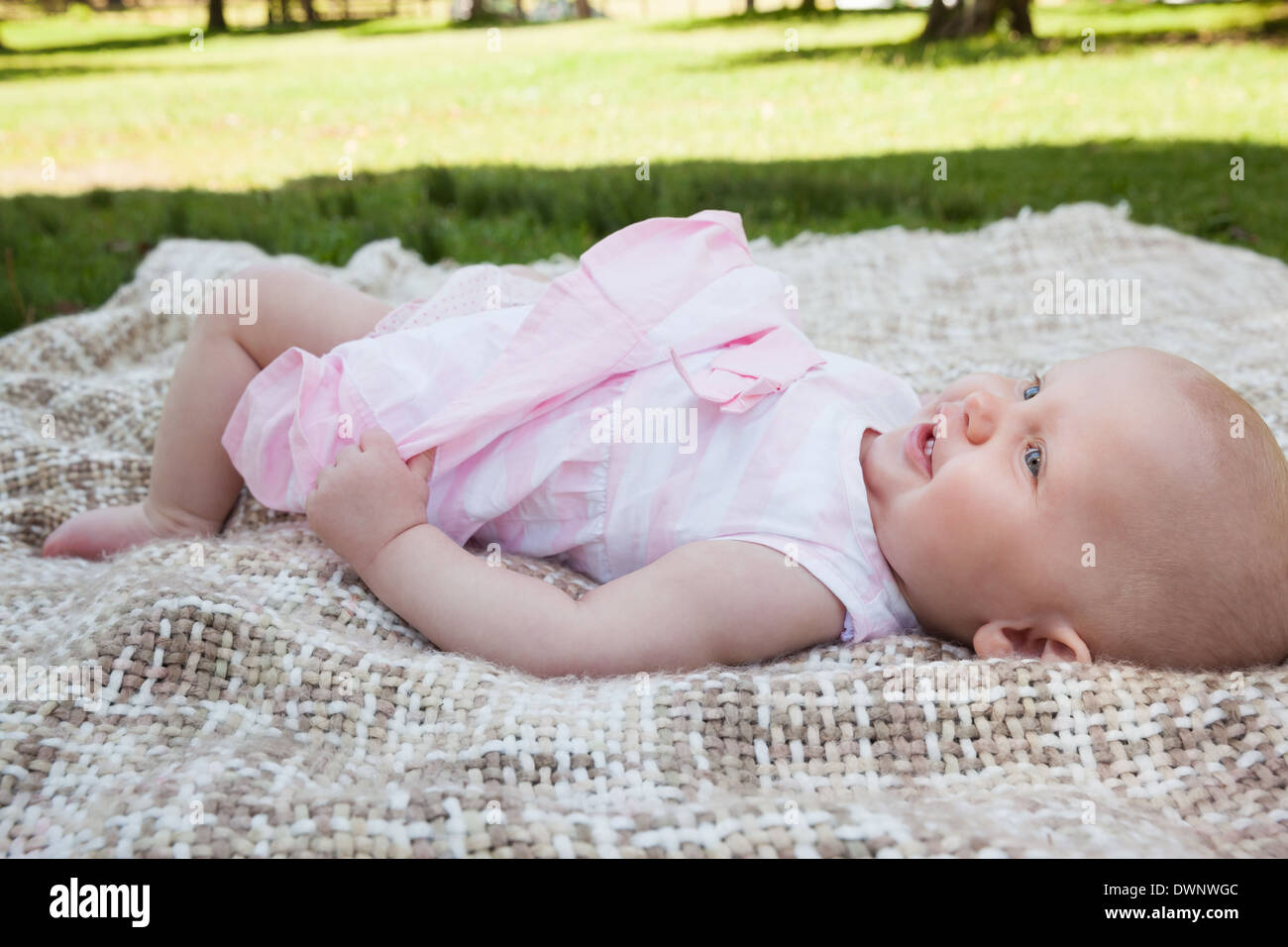 Side view of a cute baby lying on blanket at park Stock Photo - Alamy