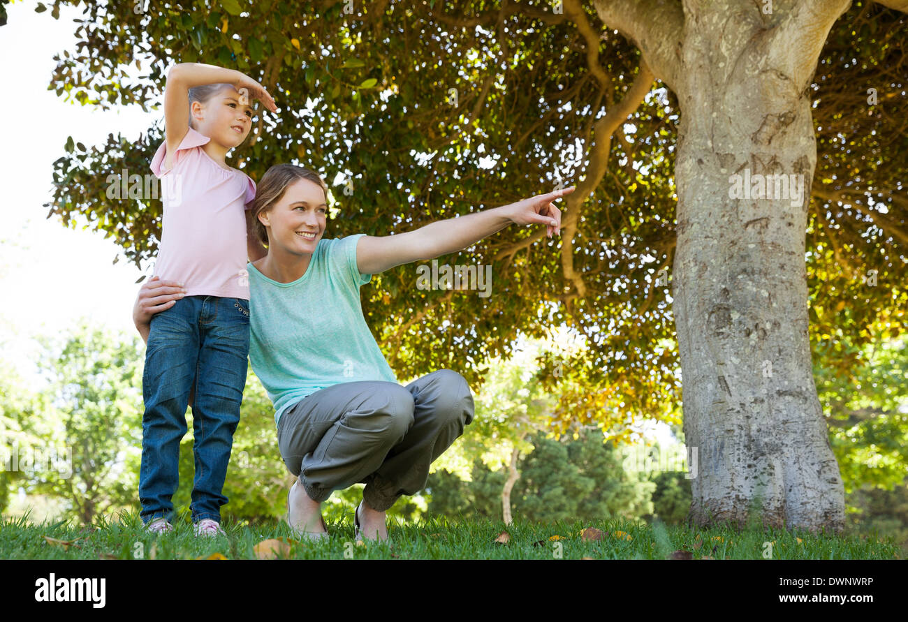 Mother pointing out at something besides daughter at park Stock Photo ...