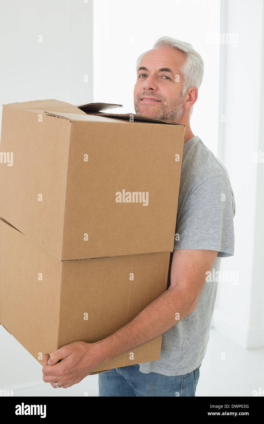 Smiling man carrying cardboard moving boxes Stock Photo - Alamy