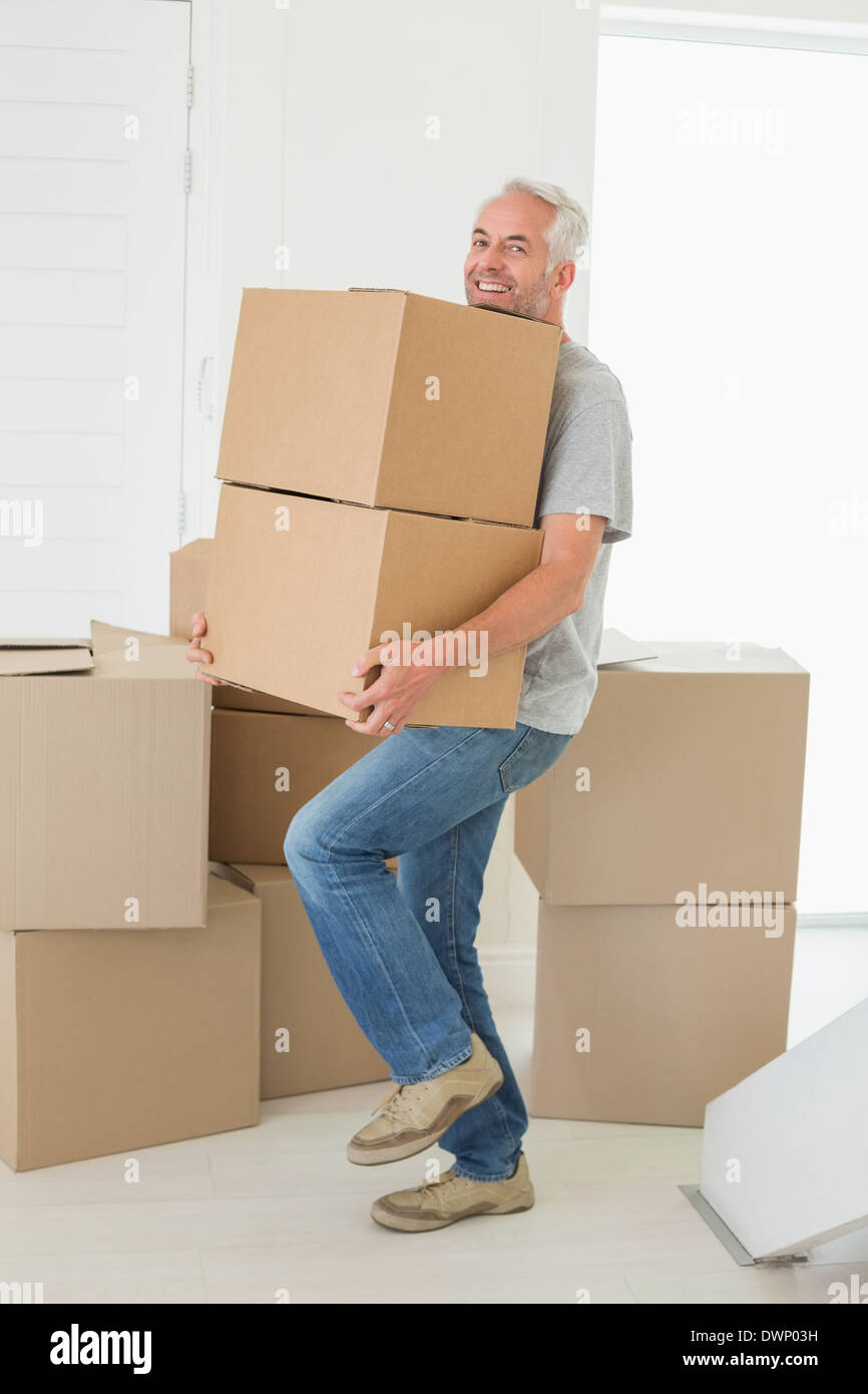 Smiling man carrying cardboard moving boxes Stock Photo - Alamy