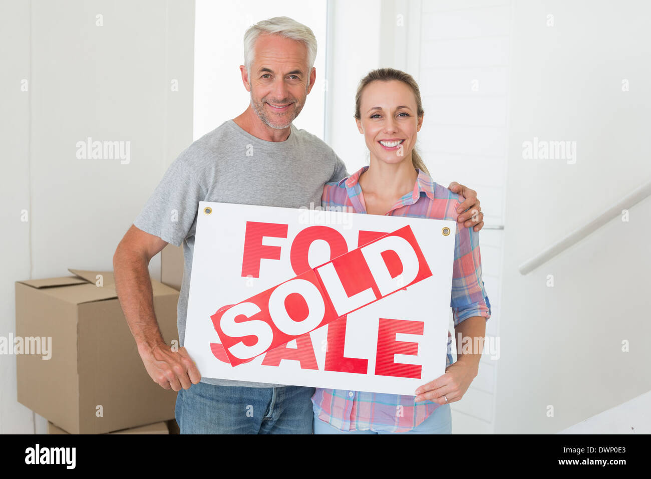 Happy couple standing and holding sold sign Stock Photo - Alamy