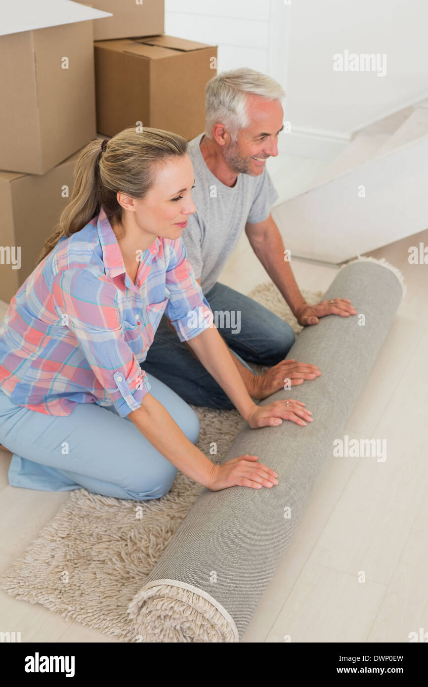 Happy couple rolling out new rug Stock Photo - Alamy