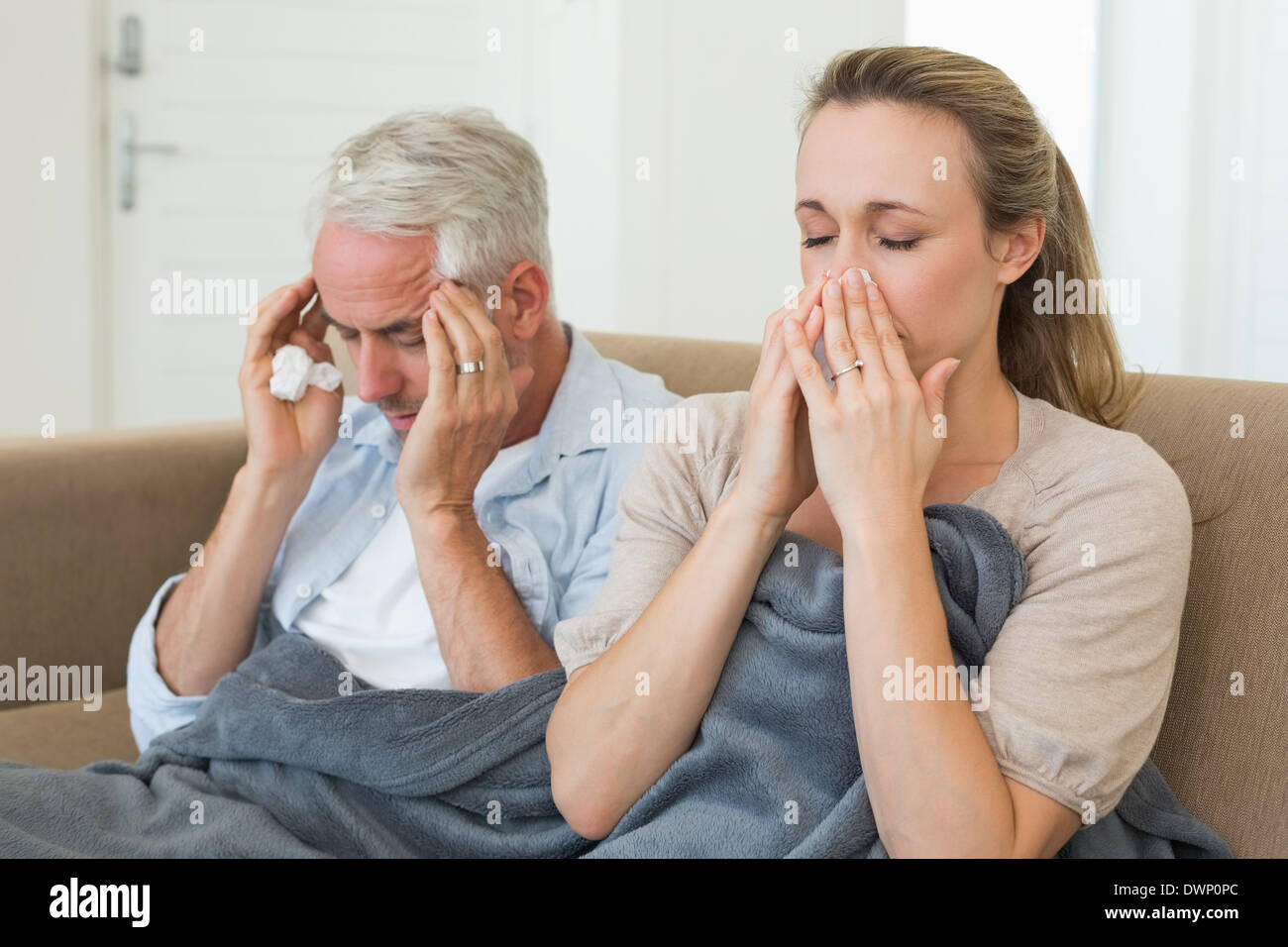 Sick couple sitting on the couch under a blanket Stock Photo - Alamy