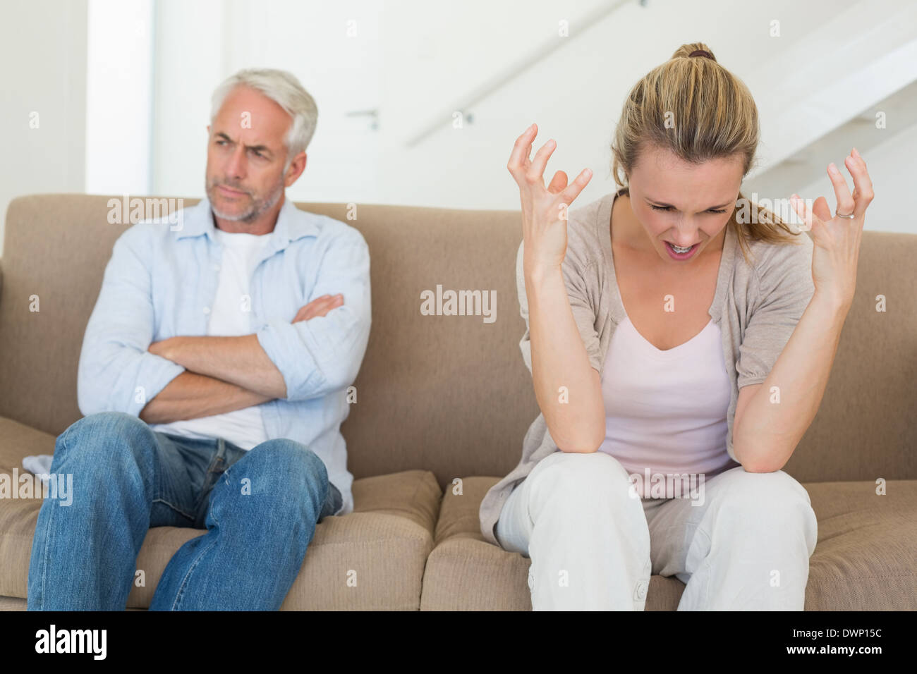 Angry couple sitting on couch arguing Stock Photo - Alamy
