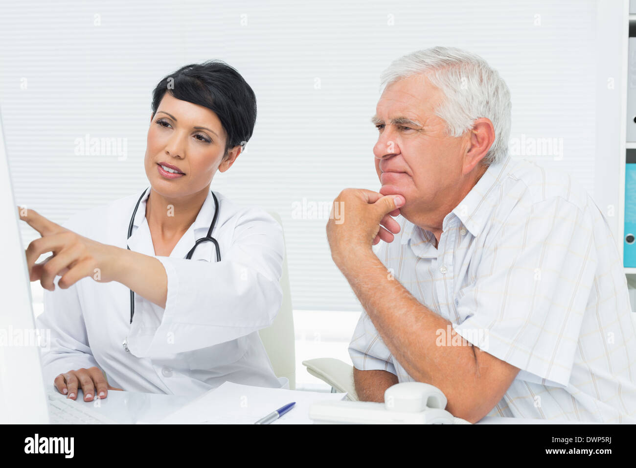 Doctor with male patient reading reports on computer Stock Photo - Alamy