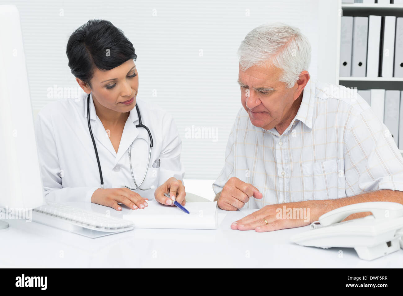 Female doctor with male patient reading reports Stock Photo - Alamy