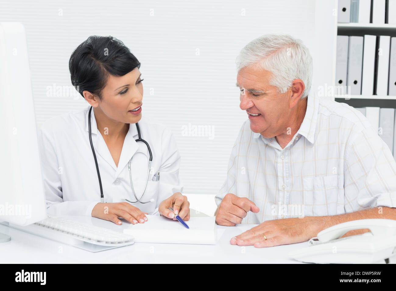 Female doctor with male patient reading reports Stock Photo - Alamy