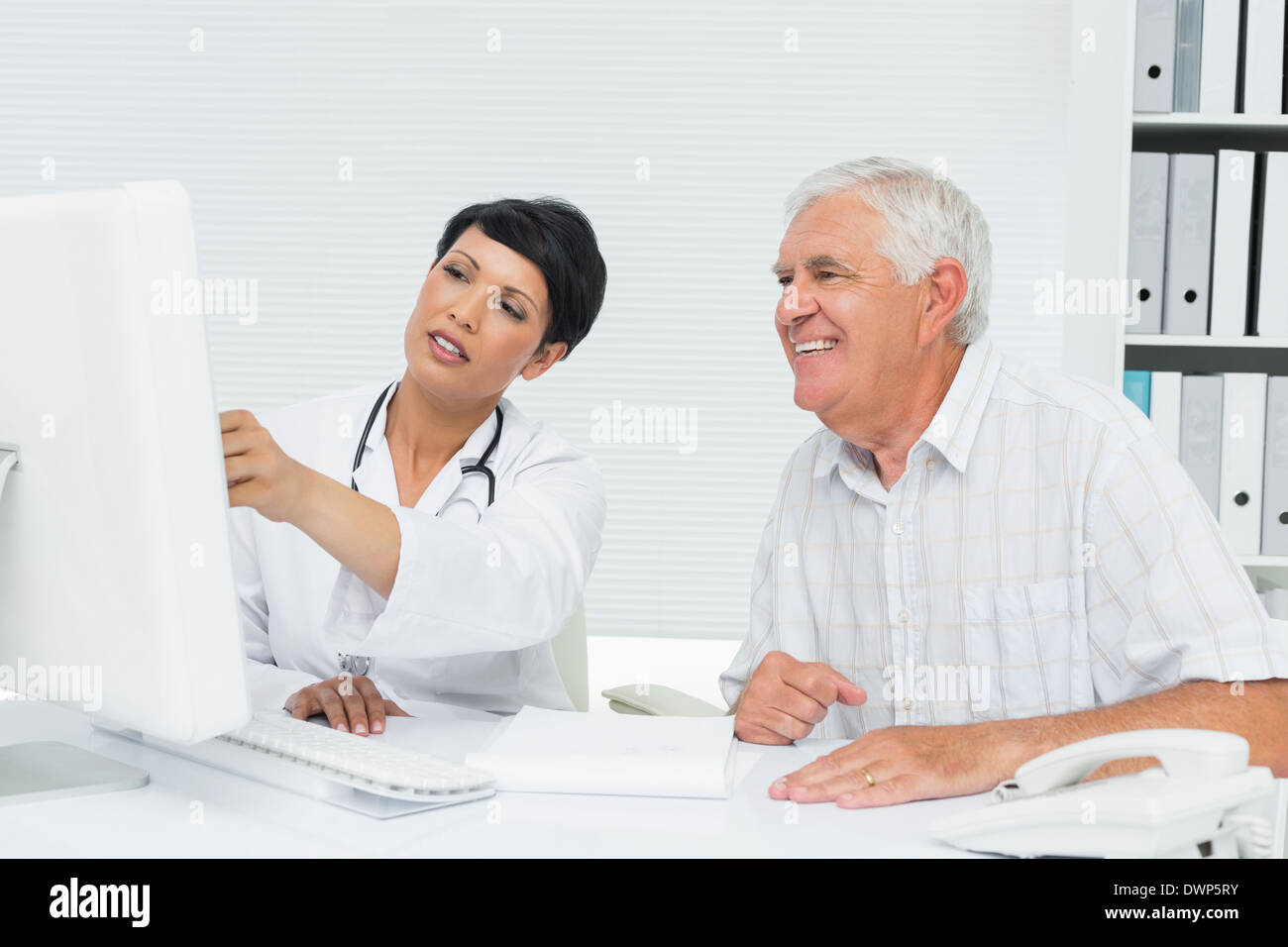 Doctor with male patient reading reports on computer Stock Photo - Alamy