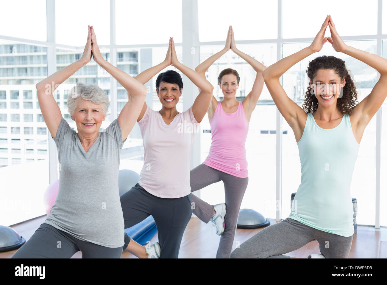 Class standing in tree pose at yoga class Stock Photo - Alamy