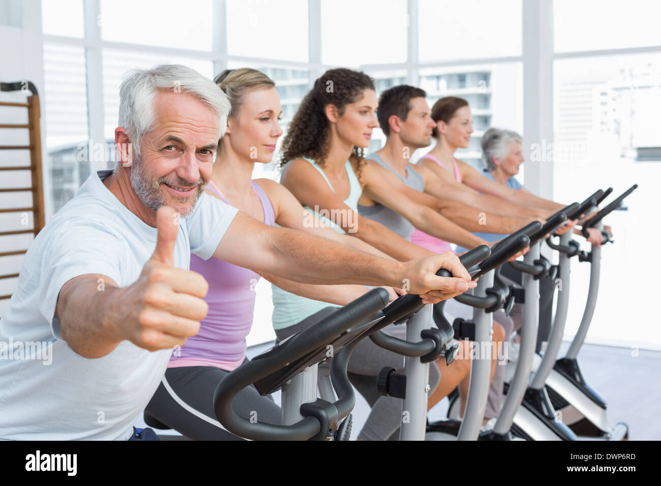 Man gesturing thumbs up with class at spinning class Stock Photo - Alamy