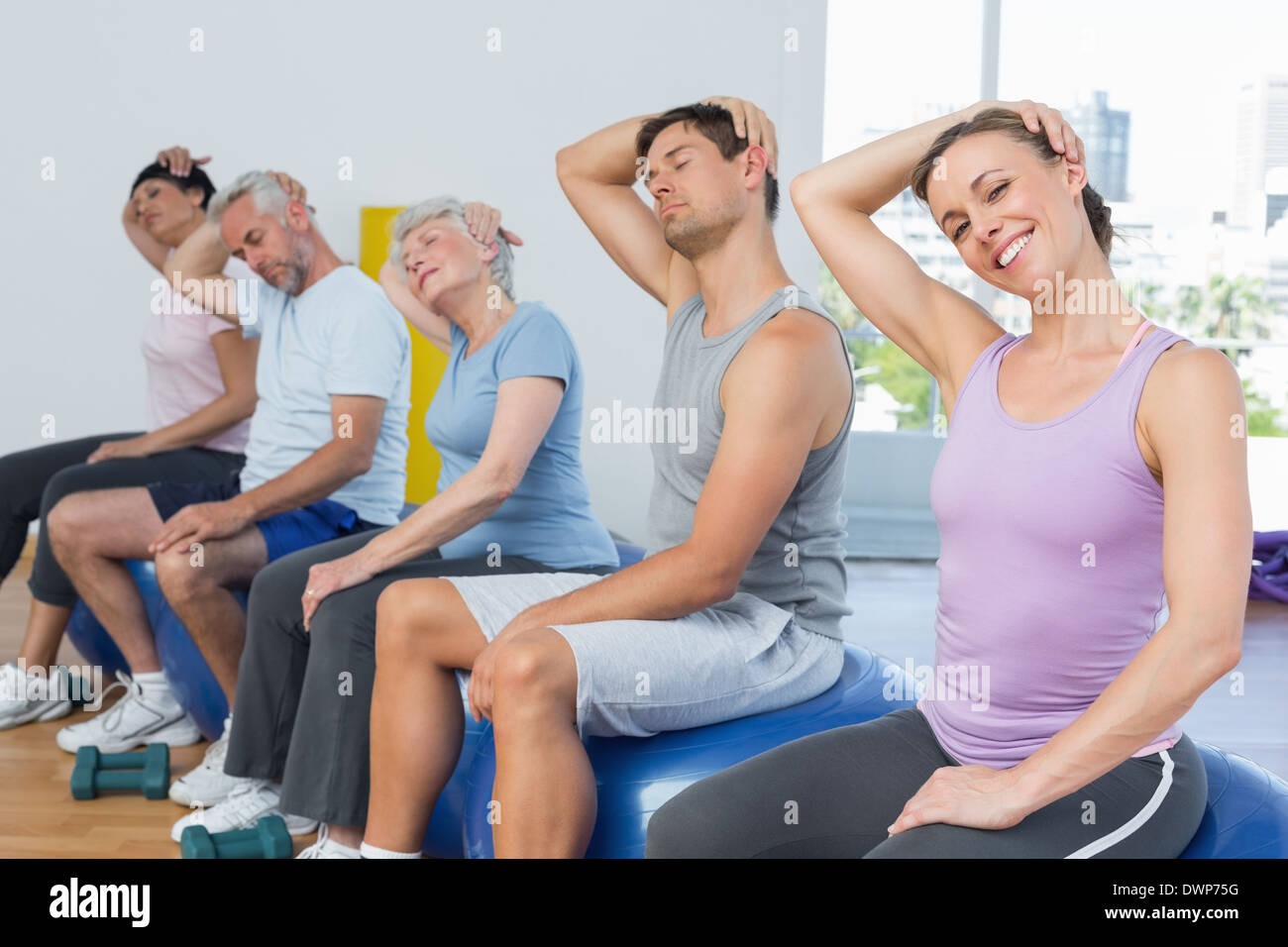Class sitting on exercise balls and stretching neck in gym Stock Photo ...
