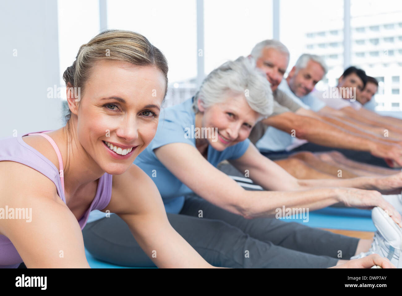 Class stretching hands to legs at yoga class Stock Photo - Alamy