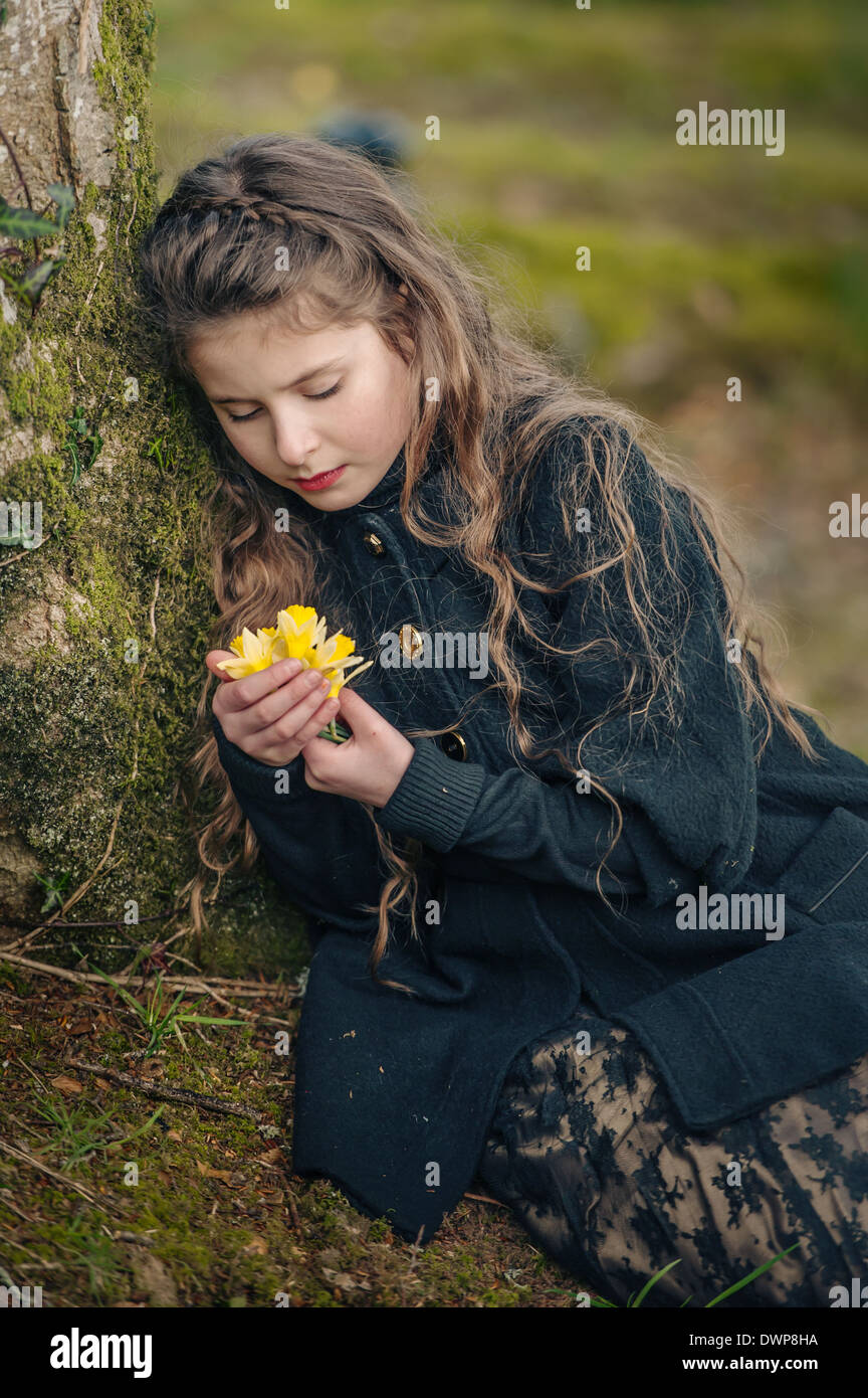 Victorian girl with daffodils in spring sitting under the tree, covered ...